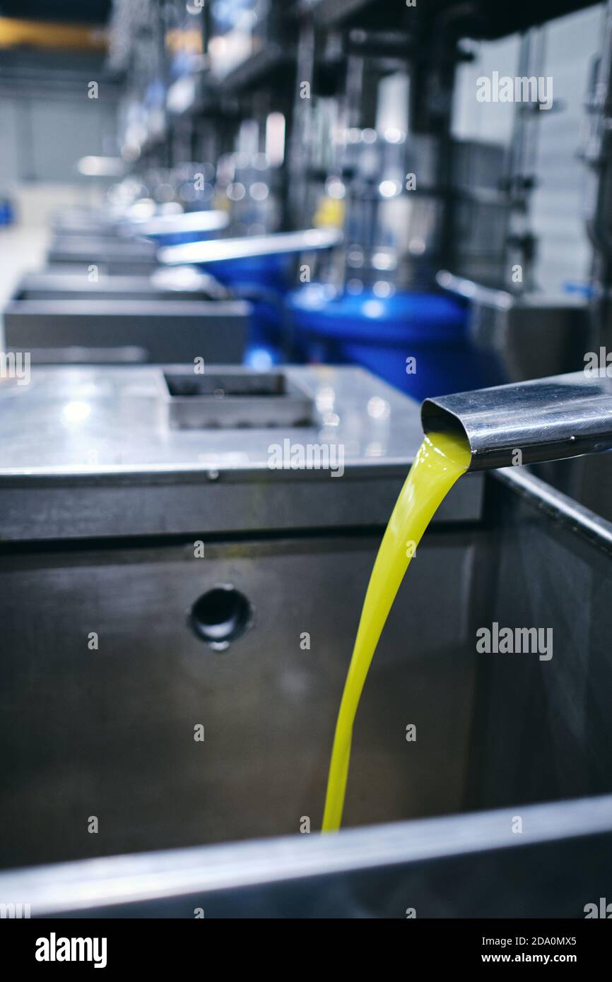 Closeup of yellow chemical liquid flowing from metal tap in industrial ...