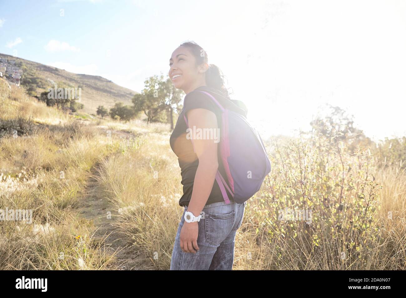 Side view of cheerful young Asian female backpacker standing on ...