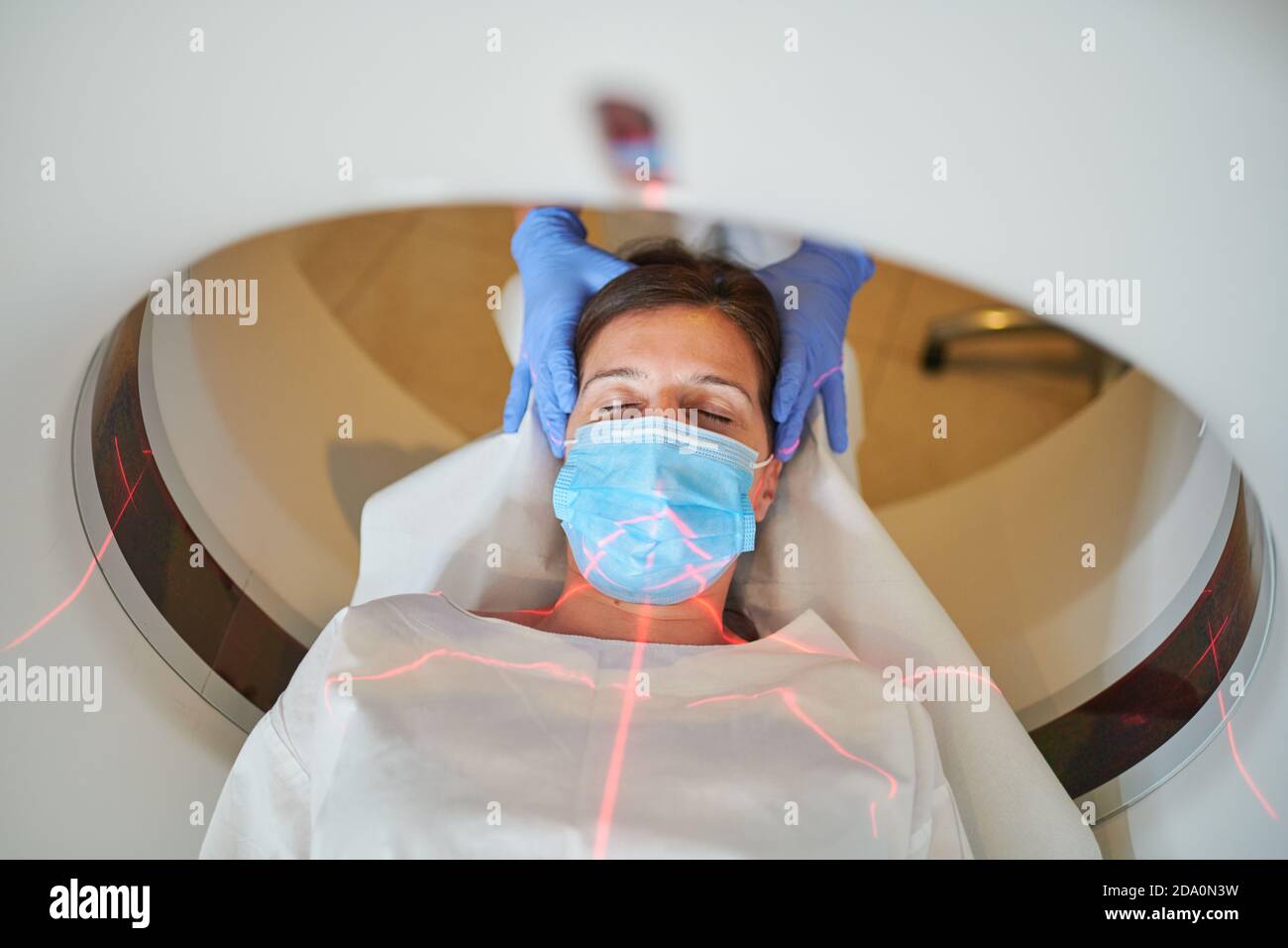 Anonymous doctor in uniform using tomography machine with lying female ...