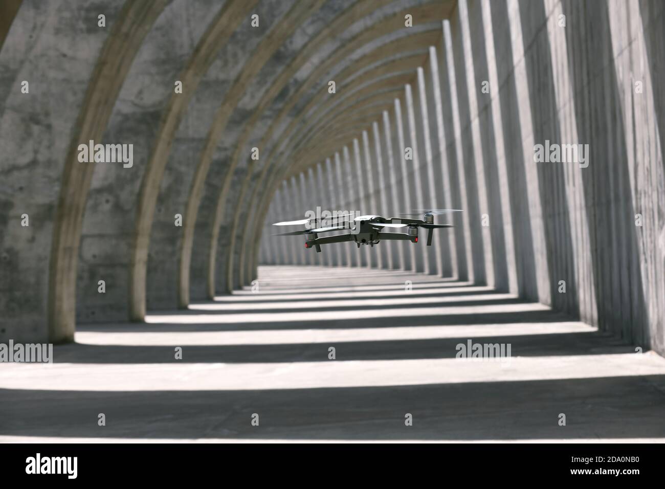 Modern drone flying in empty arched walkway with columns casting ...