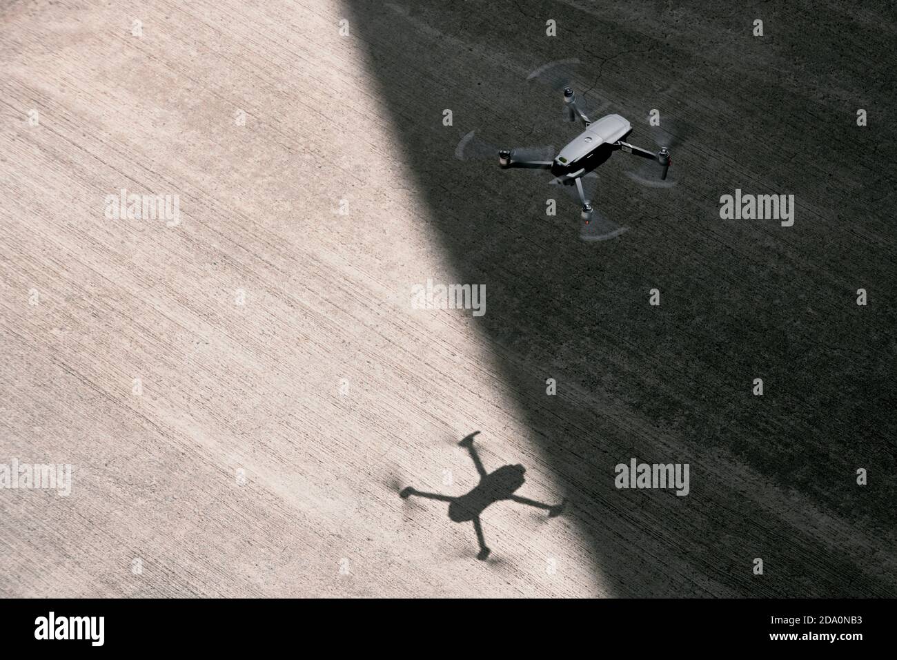 From above modern drone flying in empty concrete walkway casting ...