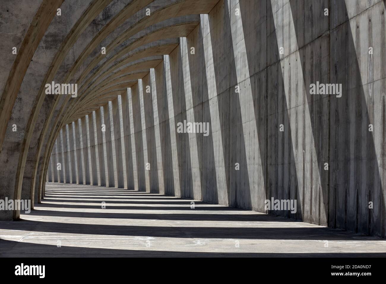 Columns of empty concrete walkway illuminated by sunlight casting lines ...