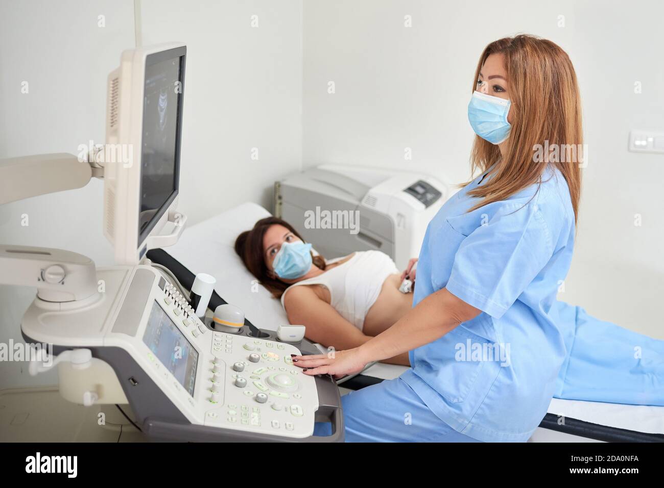 Side view of female doctor in uniform examining patient in mask while ...