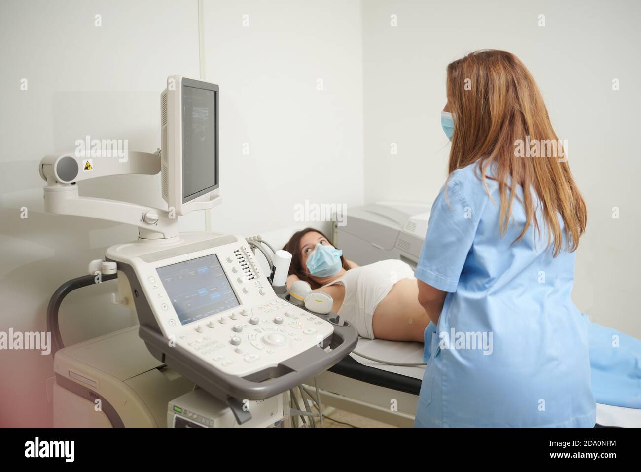 Anonymous female doctor in uniform examining patient in mask while ...