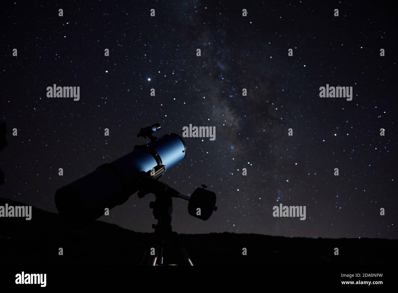 Modern optical telescope against cloudless dark sky with glowing stars ...