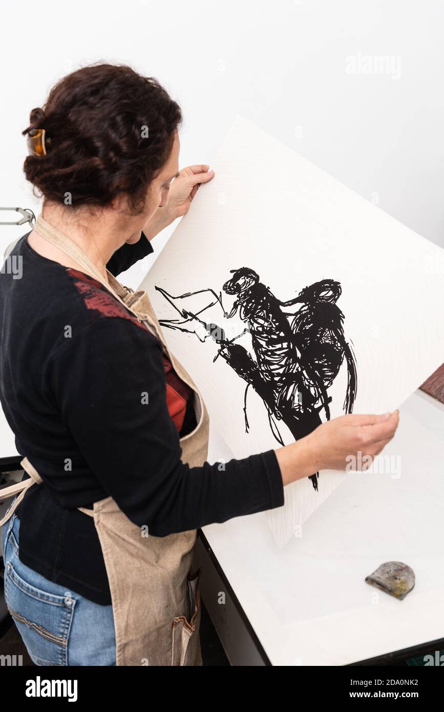 High angle side view of artisan female printmaker examining paper sheet ...