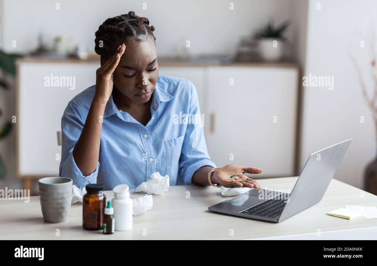 Sick black female office employee sitting at workplace taking lots of ...