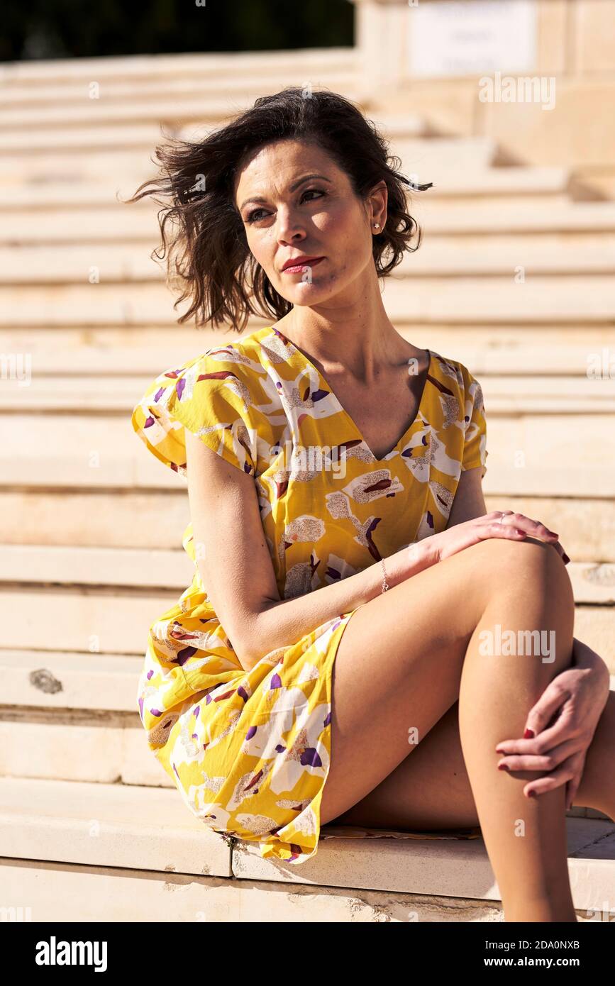 Side view of dreamy young slender female in short yellow summer dress ...