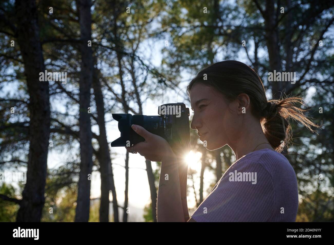 Side view of young female photographer with professional photo camera ...