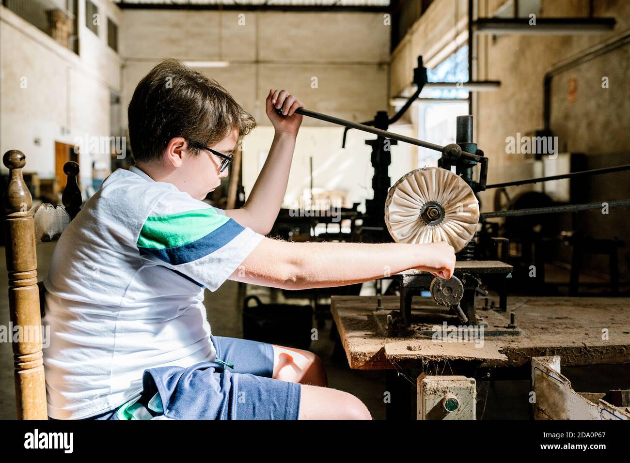 Focused teenage boy working with old drill press while polishing detail ...
