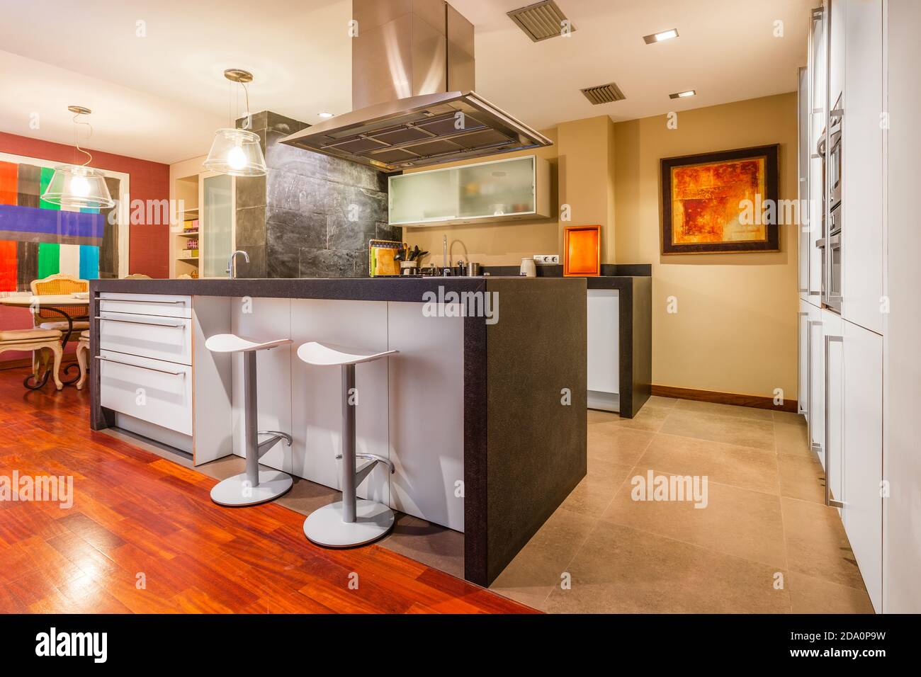 Contemporary kitchen with steel hood and bar counter lighted with ...