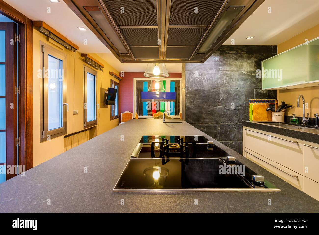 Contemporary kitchen with steel hood and bar counter lighted with ...