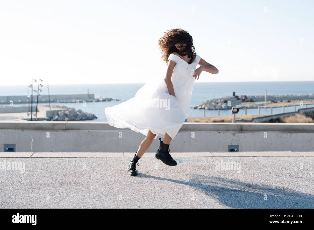 Side view of rebellious female in elegant white dress and brutal boots ...