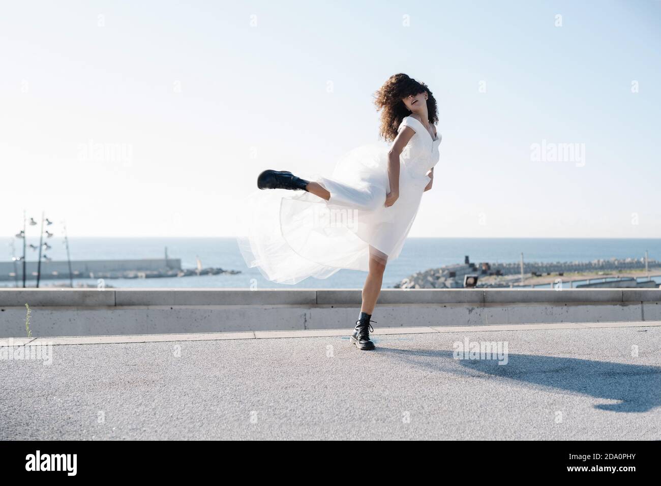 Side view of rebellious female in elegant white dress and brutal boots ...