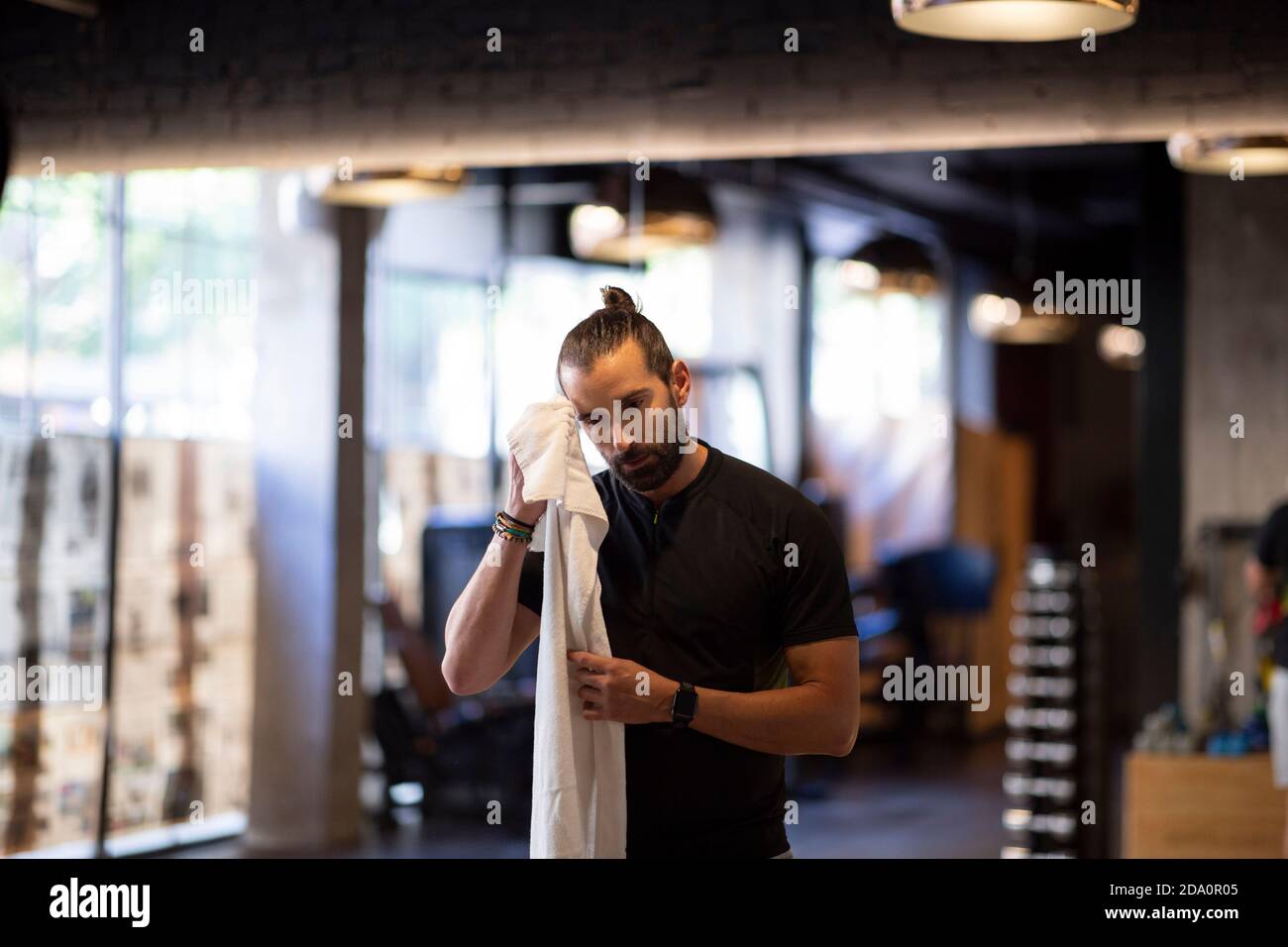 Bearded adult sportsman wiping sweat from forehead with towel during ...