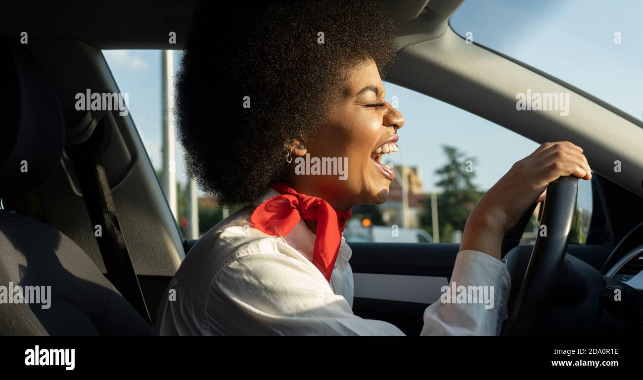 Side view of African American female driver driving automobile and ...