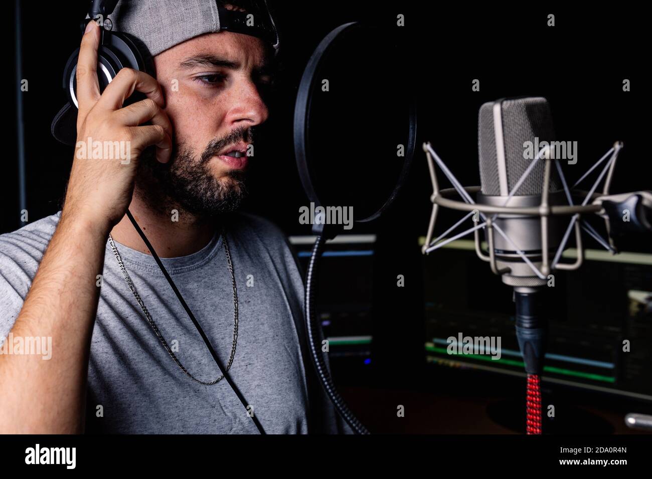 Side view of male singer in headphones and hat standing in acoustic ...