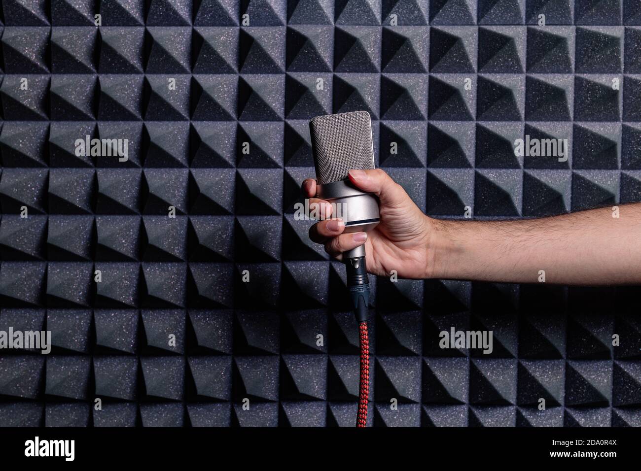 Unrecognizable crop male artist standing with modern wired microphone ...