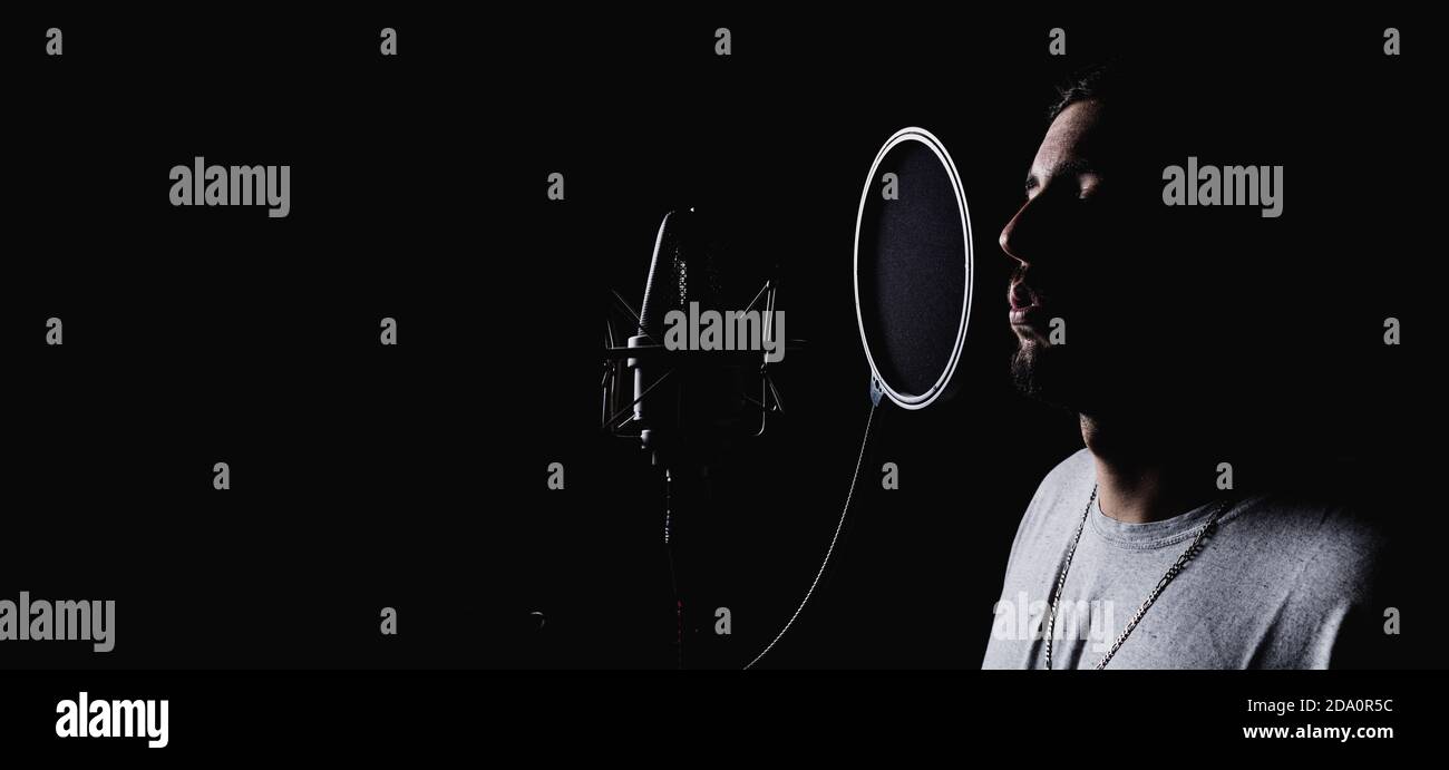 Talented male singer recording music in front of modern microphone in ...