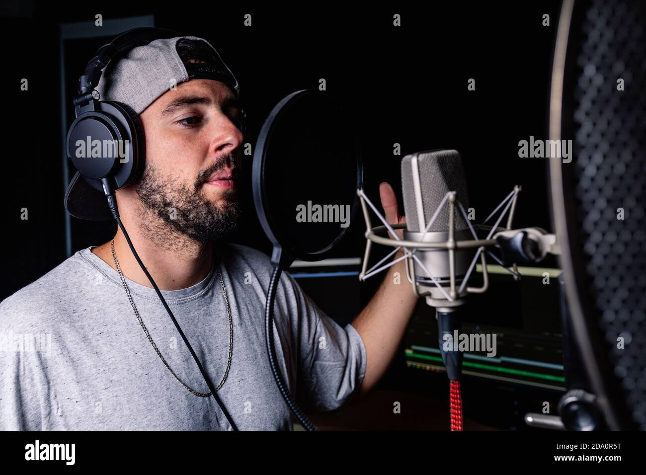 Side view of male singer in headphones and hat standing in acoustic ...