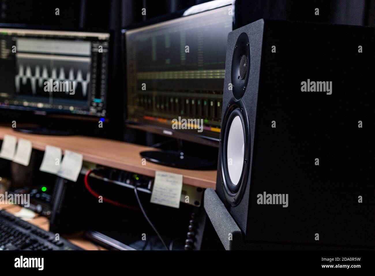 Contemporary stereo speaker placed on table with monitors in dark music ...
