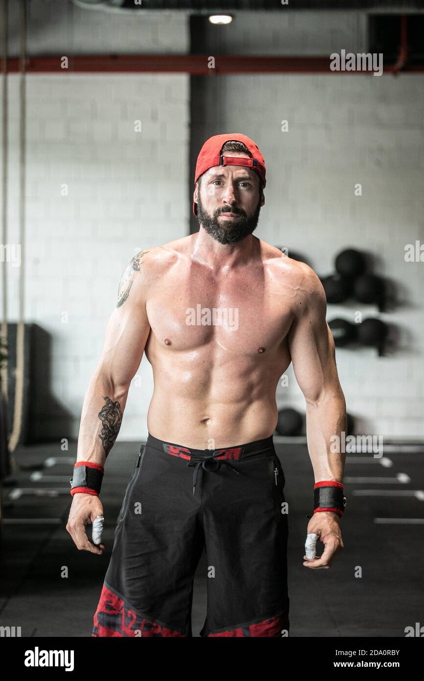 From above side view of male gardener mowing grassy lawn near bushes ...