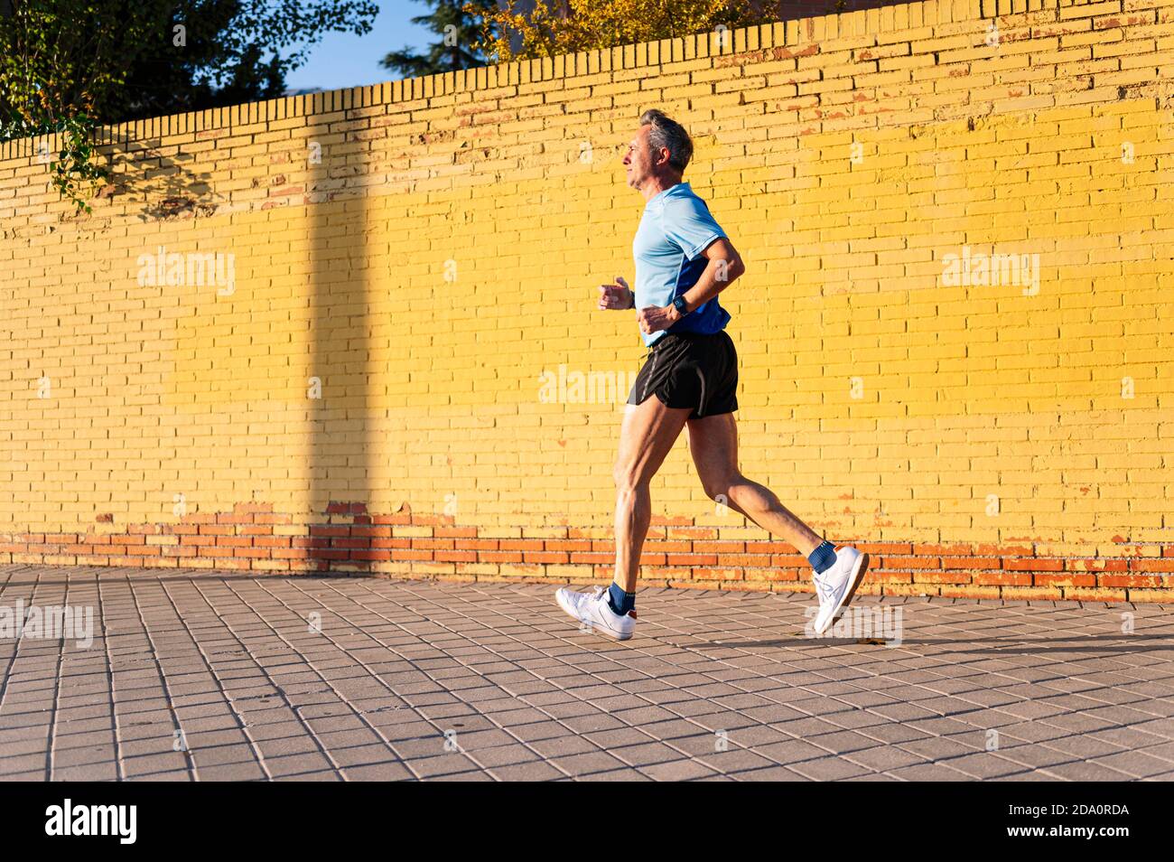 Senior retired man running through the city on yellow background Stock ...
