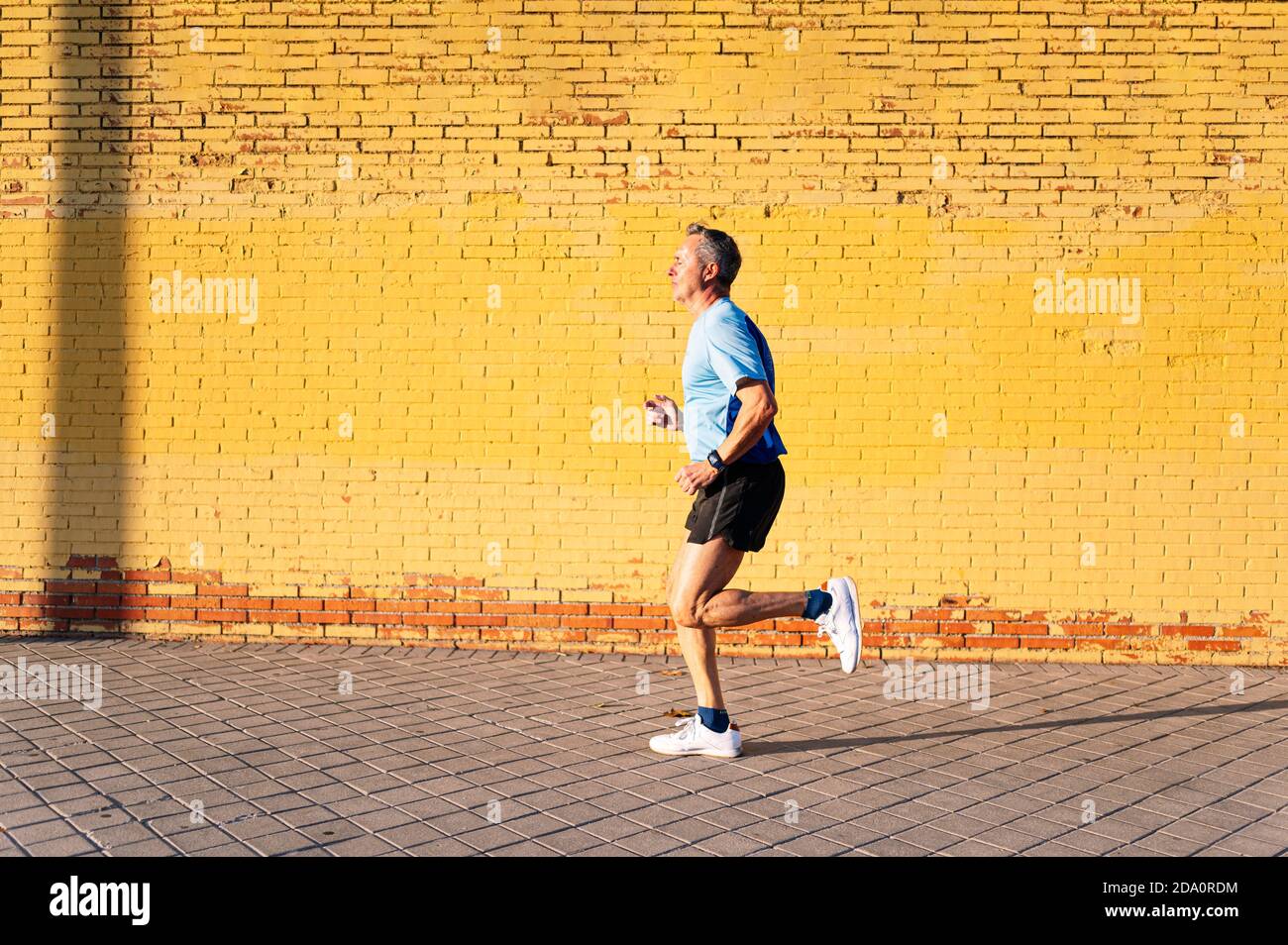 Senior retired man running through the city on yellow background Stock ...