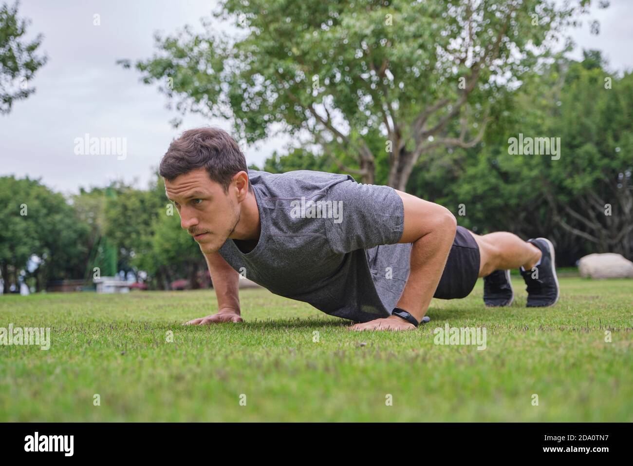 Low angle of strong male athlete doing push ups during training on ...