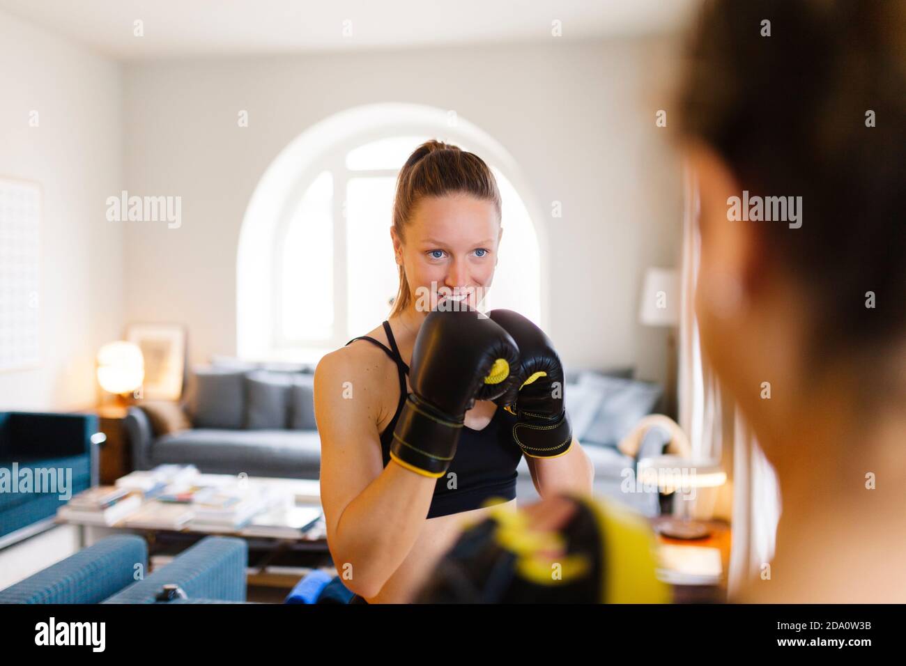 Fit female fighter in gloves and personal coach in boxing mitts ...