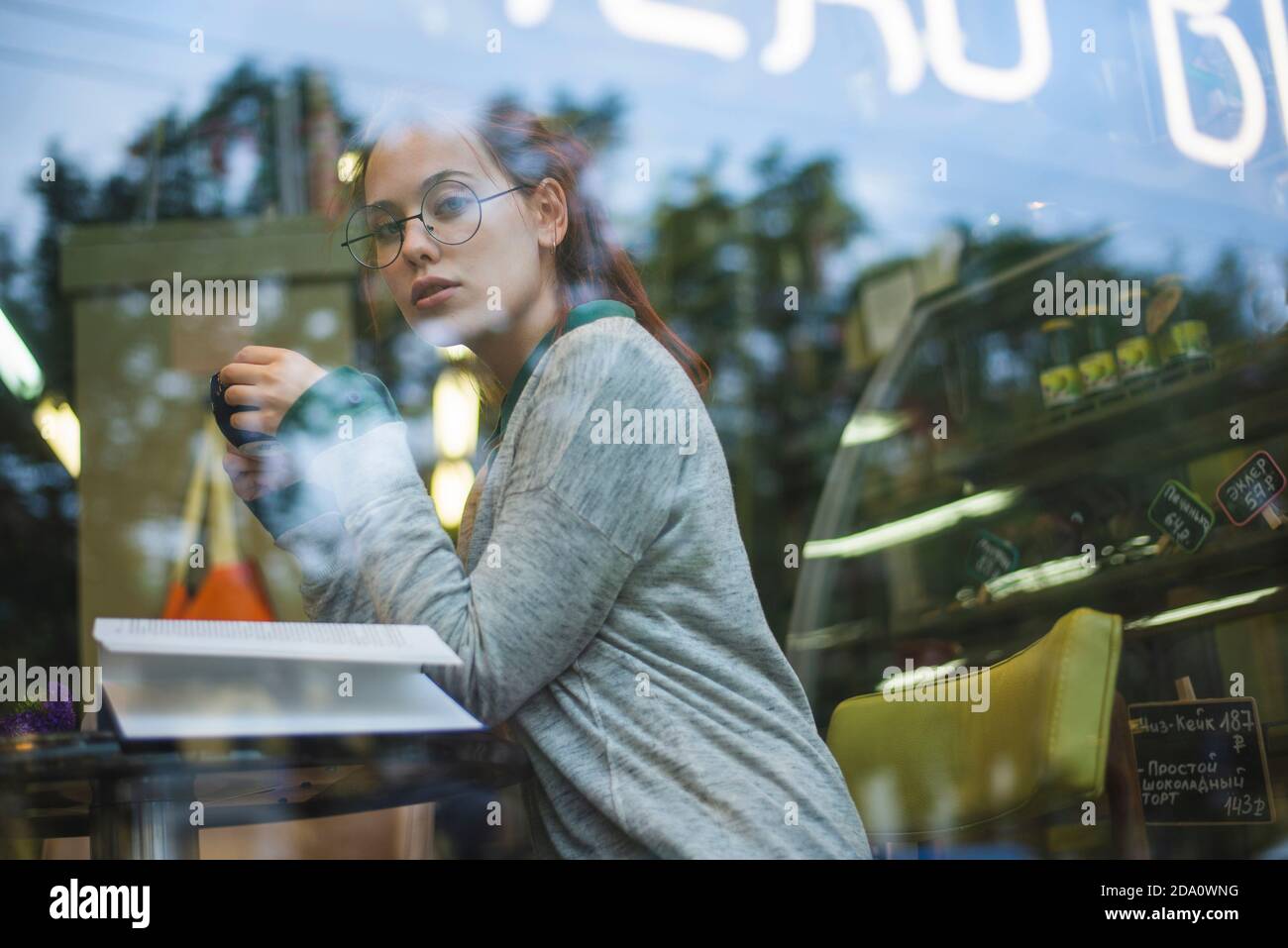 Through glass side view of relaxed female in casual outfit sitting at ...