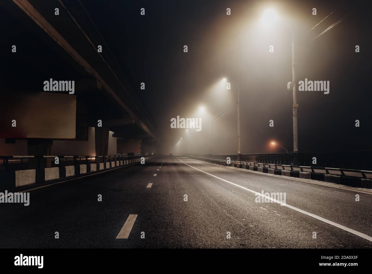 Foggy misty night road illuminated by street lights Stock Photo - Alamy
