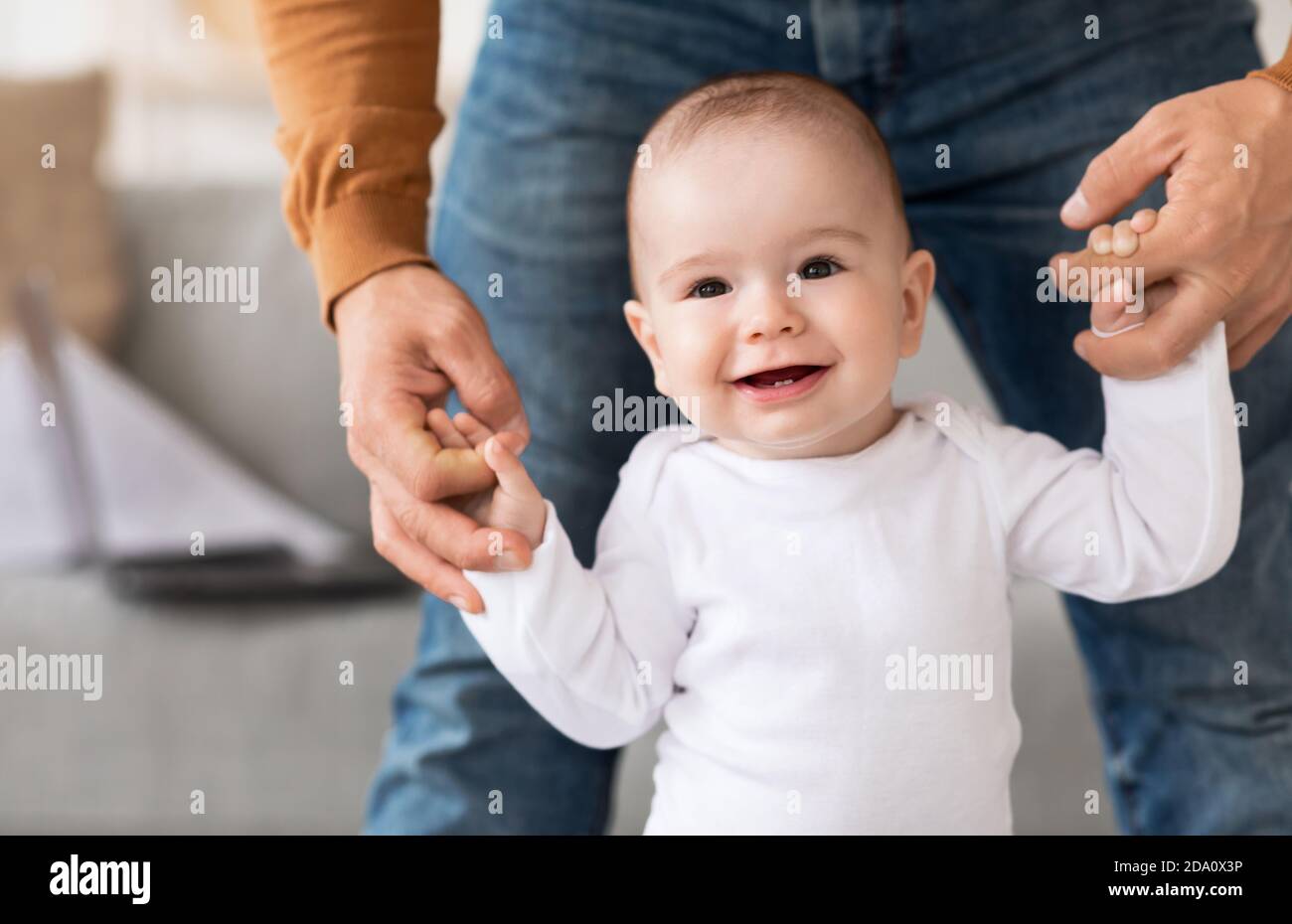 Smiling Baby Toddler Making First Steps Holding Father's Hands Indoors ...