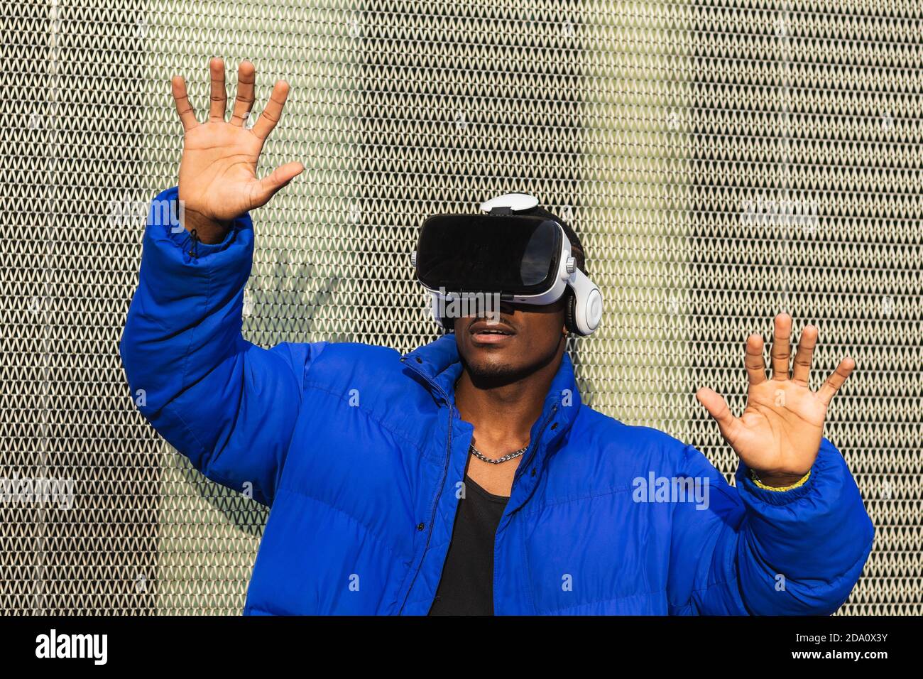 African American male standing on street near metal fence while ...