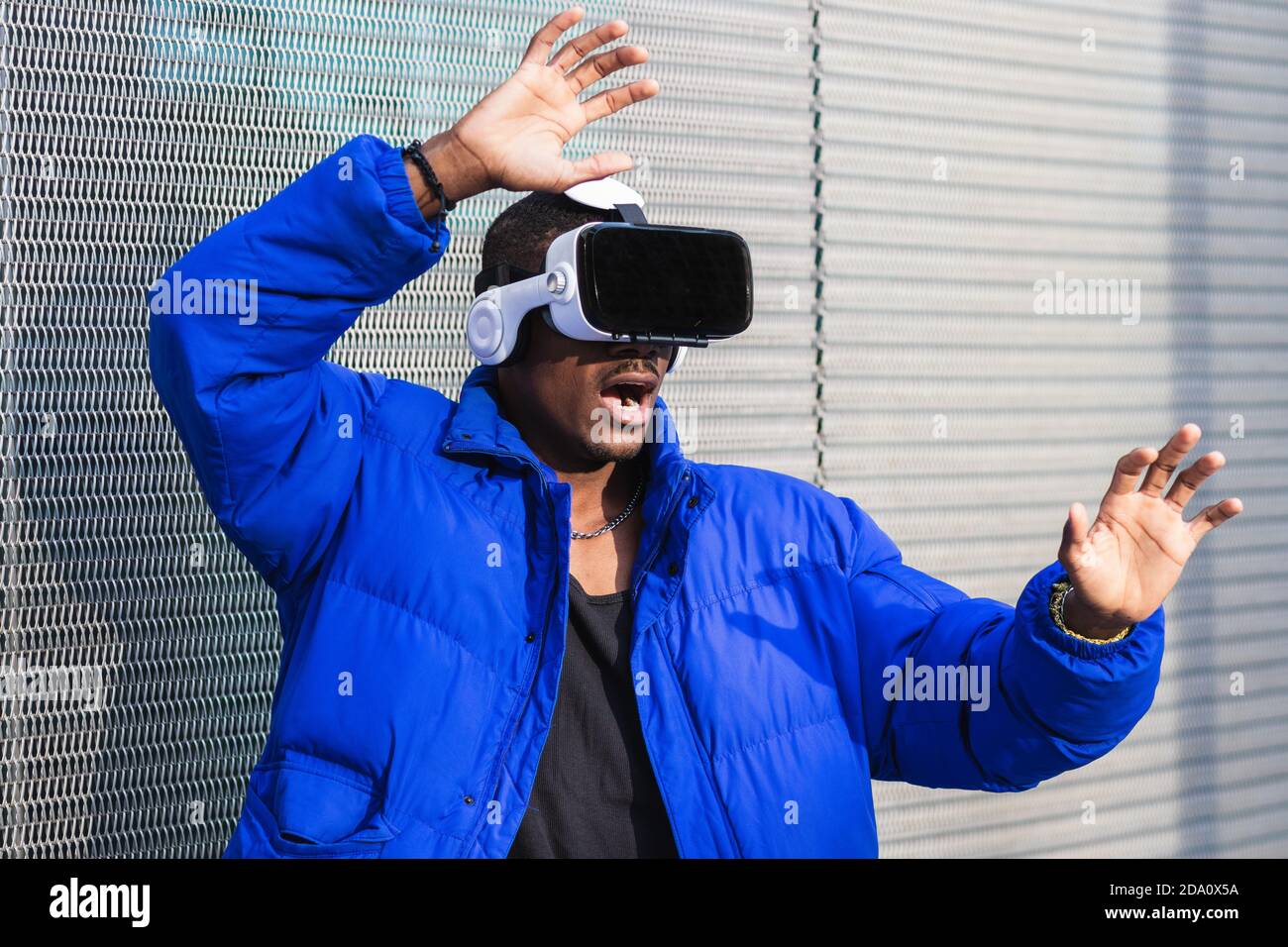 African American male standing on street near metal fence while ...