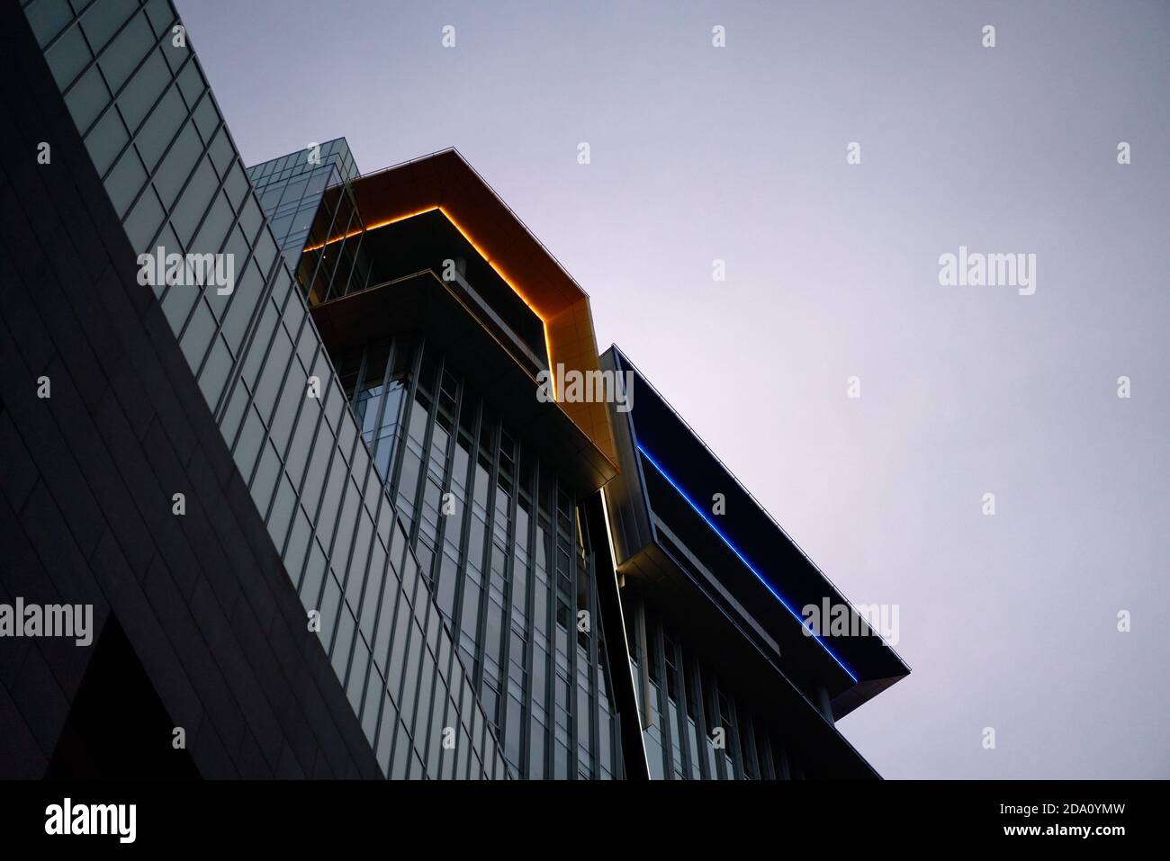 Bottom view of modern building with glass windows, gloomy sky during ...