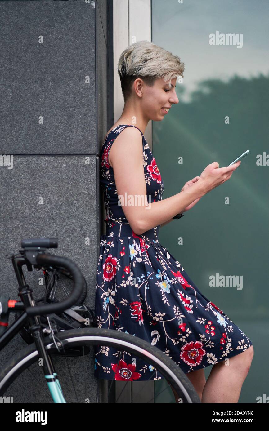 Side view of Woman with phone in hands stands near modern building on ...