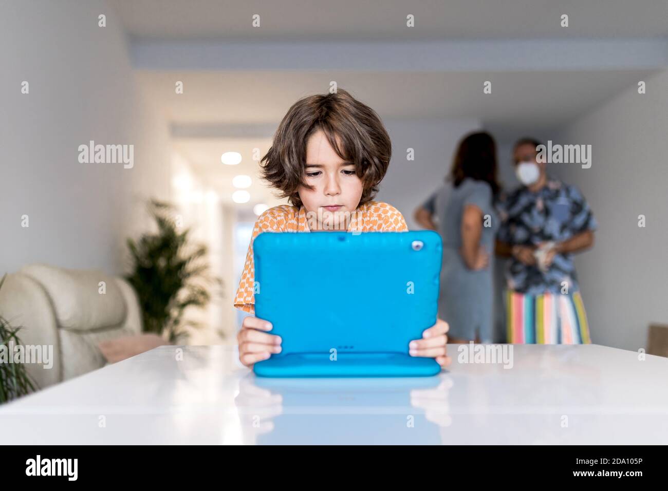 Concentrated child with netbook at table behind anonymous mother and ...