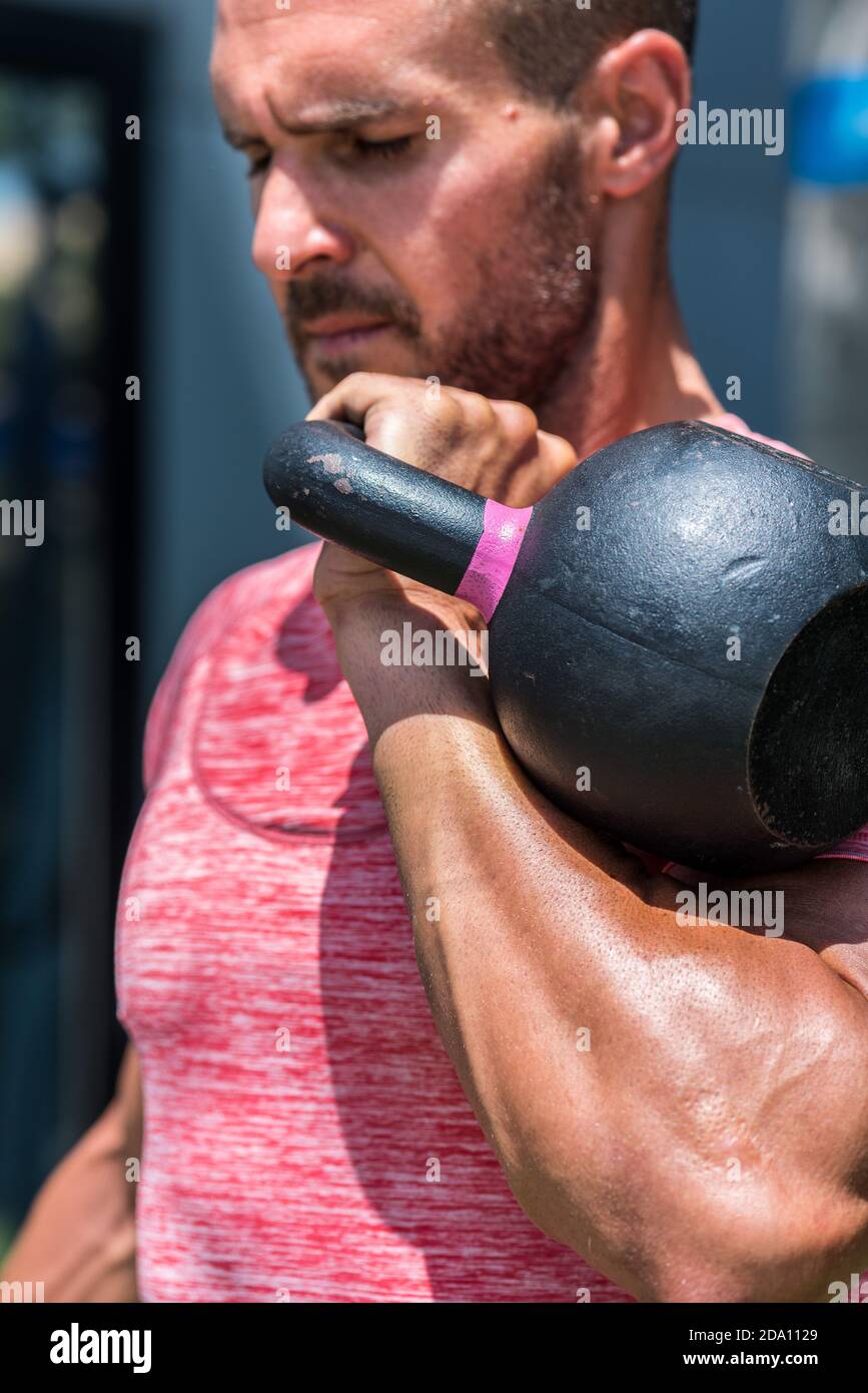 Serious male athlete with strong body doing exercises with heavy metal ...