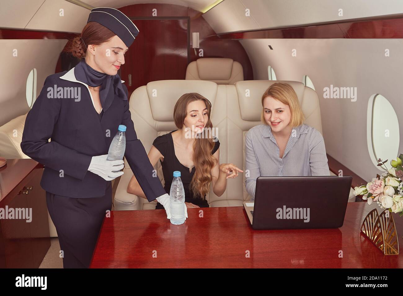 Flight attendant gives water to first class passengers inside airplane ...