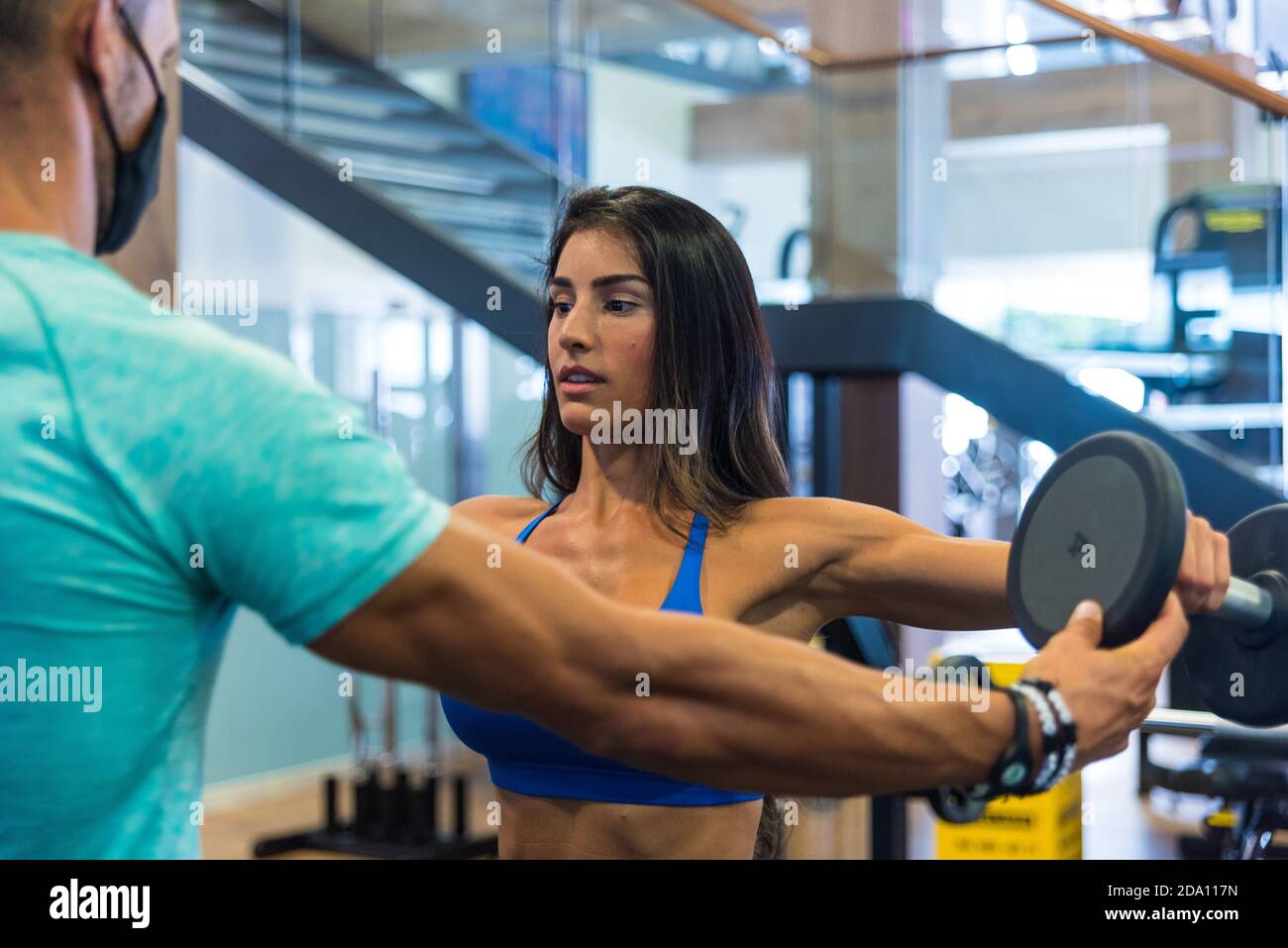 Strong female athlete doing exercises with dumbbells with support of ...