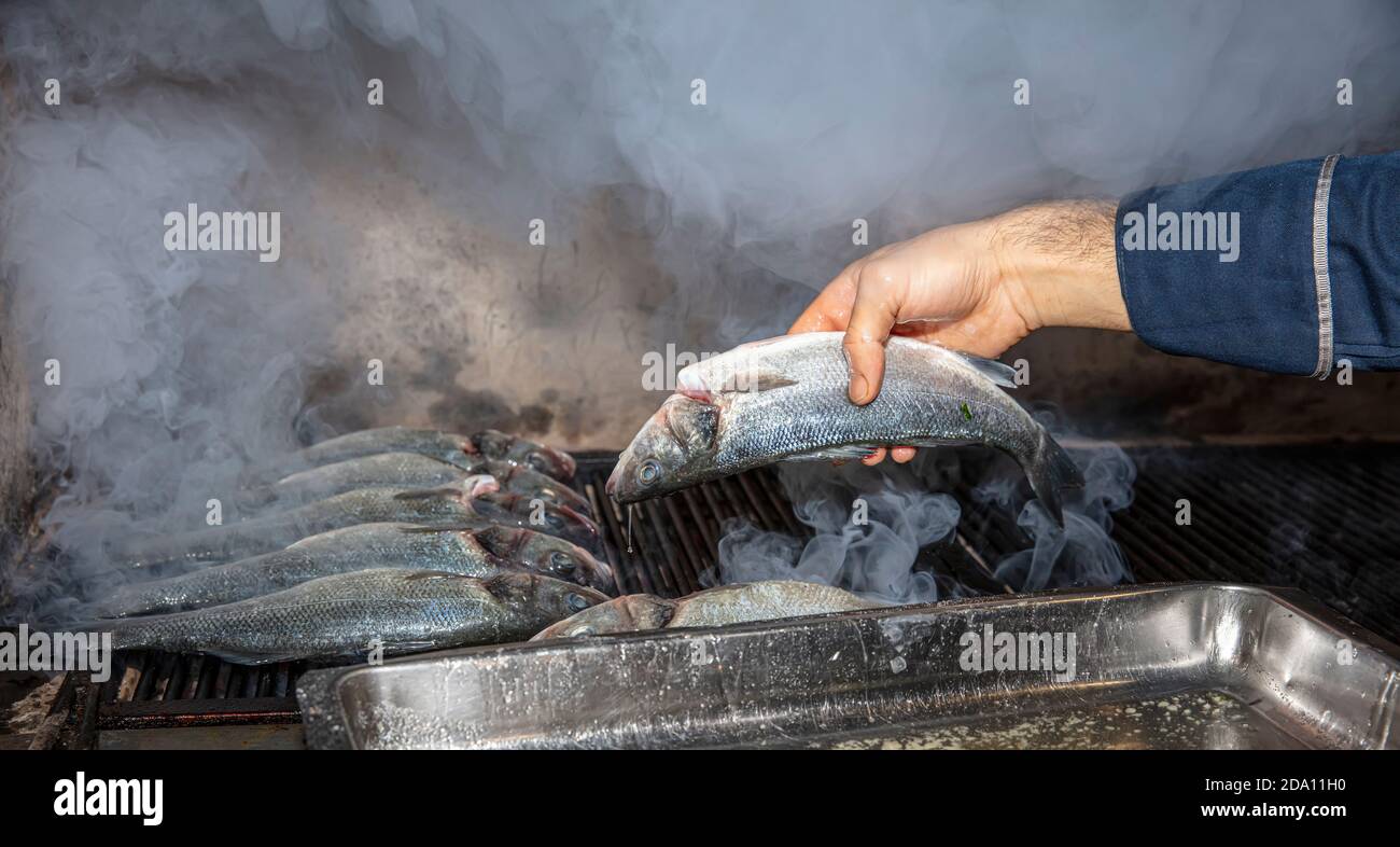 Grilled sea bass fish closeup. In process. European sea-bass, chef is ...