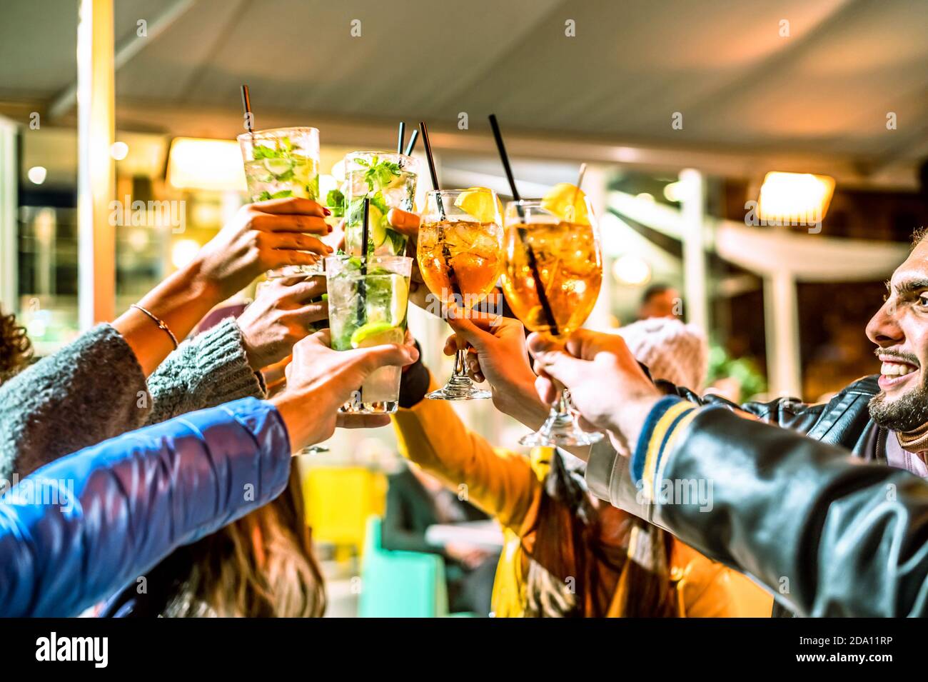 Group of happy friends drinking and toasting cocktail at bar ...