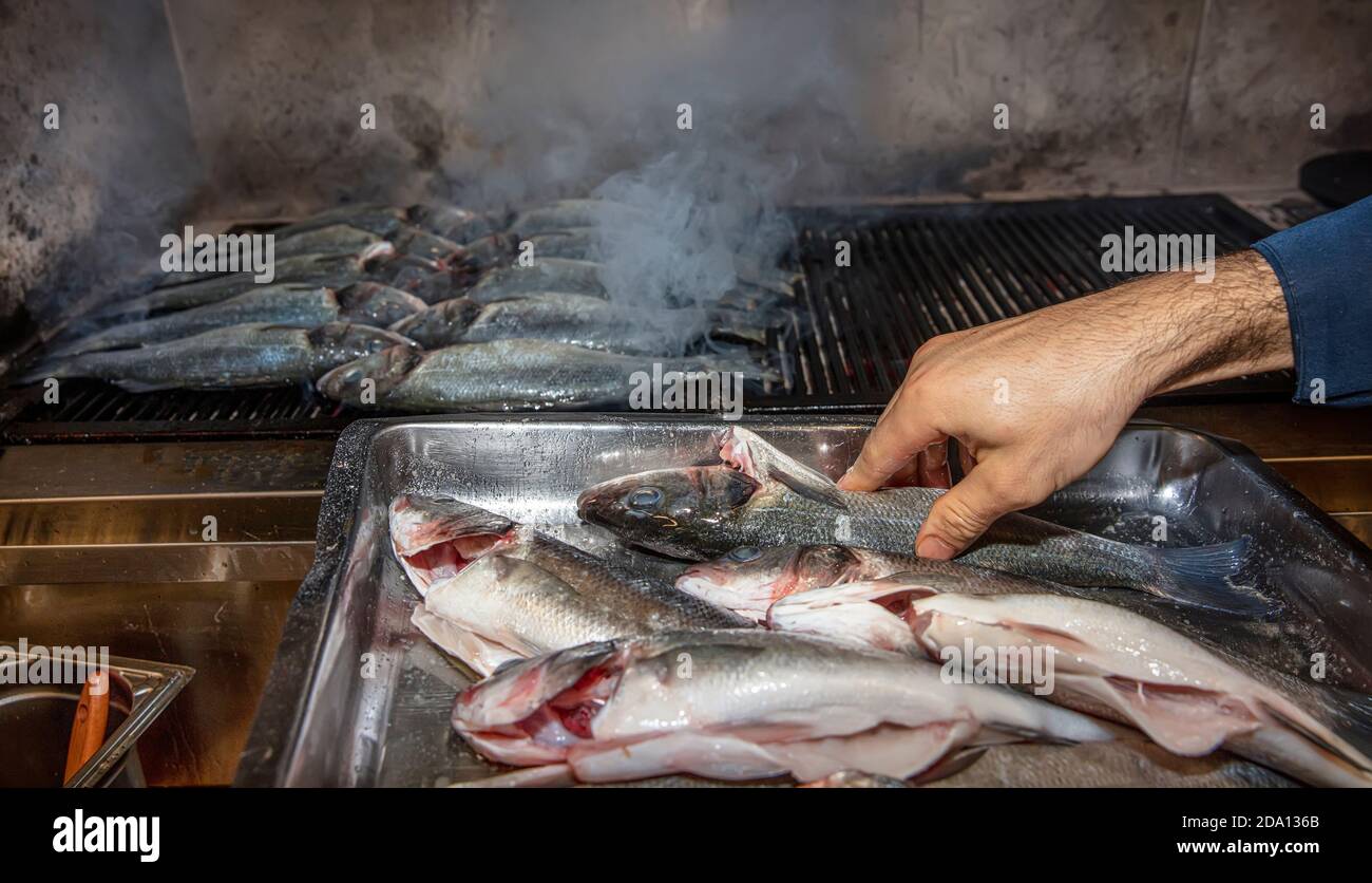 Grilled sea bass fish closeup. In process. European sea-bass, chef is ...