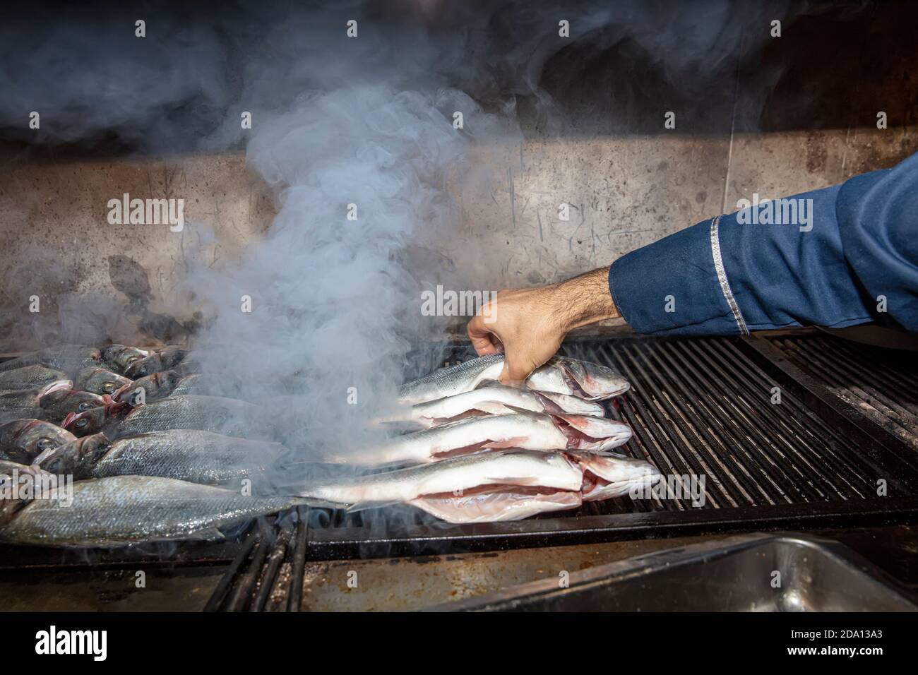 Grilled sea bass fish closeup. In process. European sea-bass, chef is ...