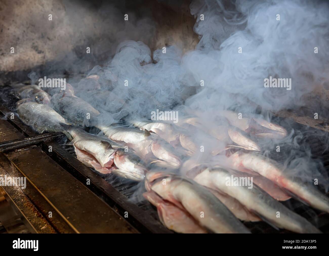 Grilled sea bass fish closeup. In process. European sea-bass, chef is ...
