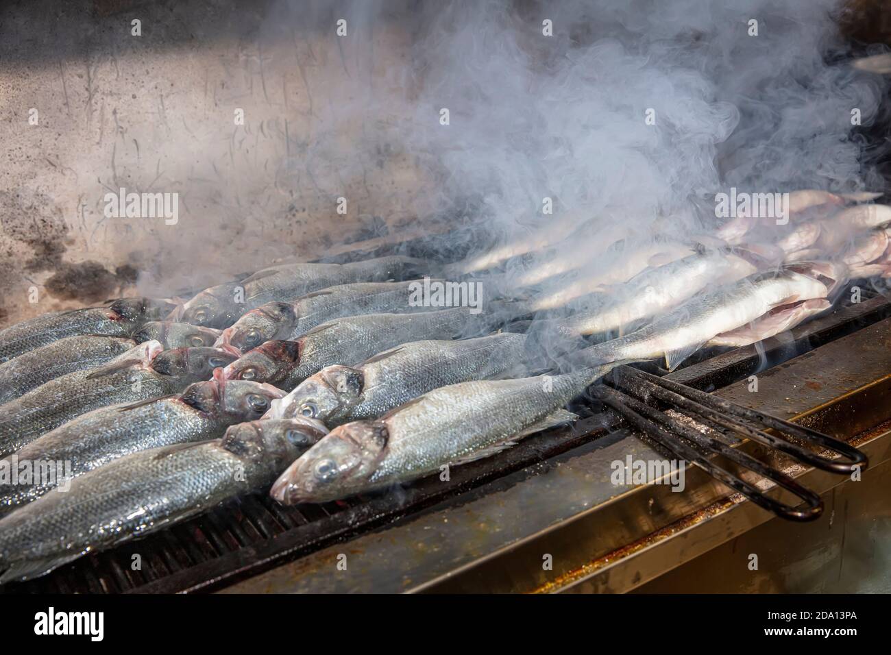 Grilled sea bass fish closeup. In process. European sea-bass, chef is ...