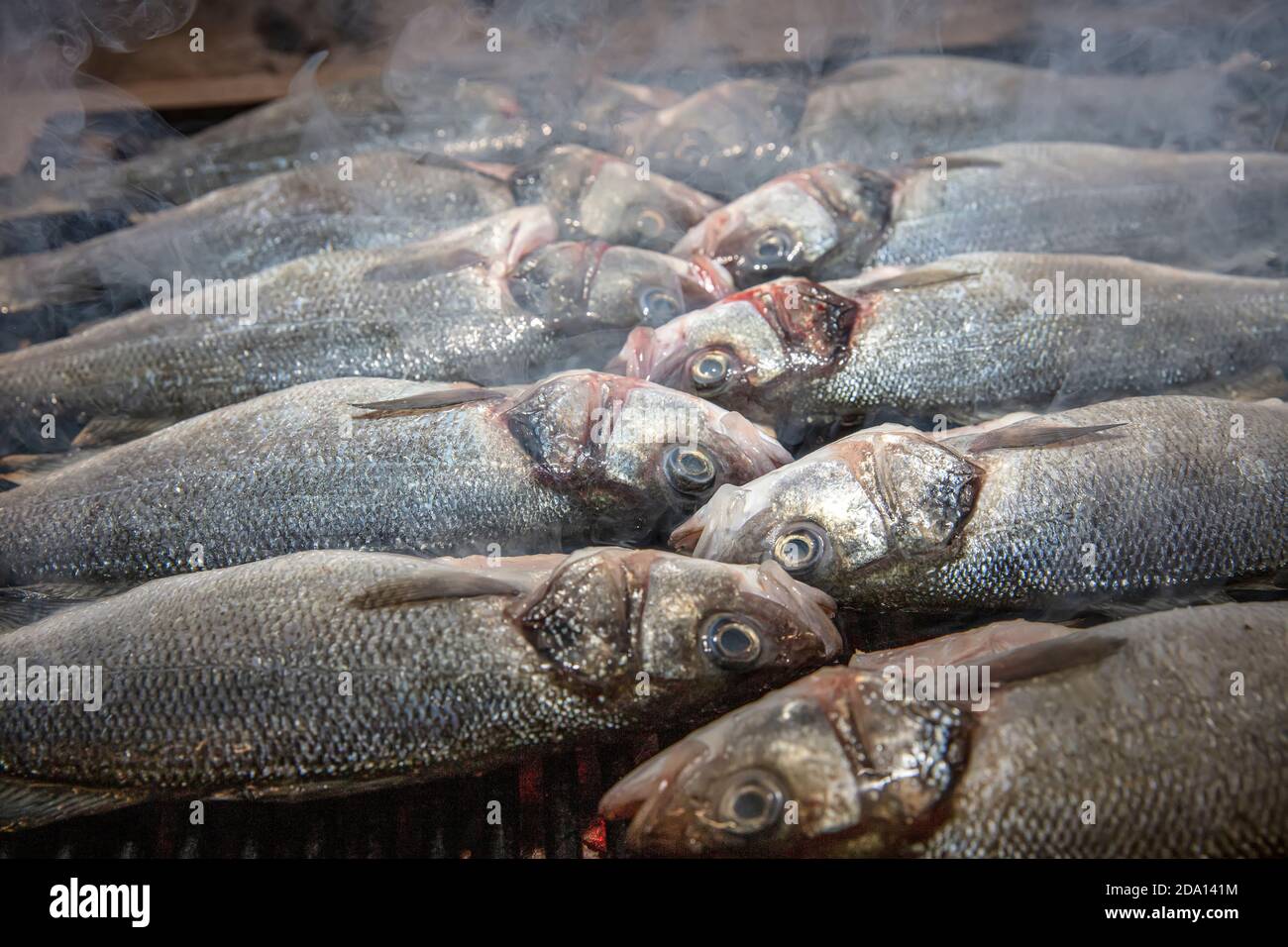 Grilled sea bass fish closeup. In process. European sea-bass, chef is ...
