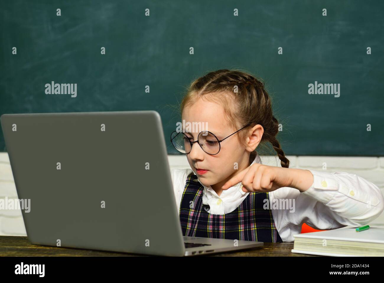 Back to school. Pupil working on laptop computer over blackboard ...