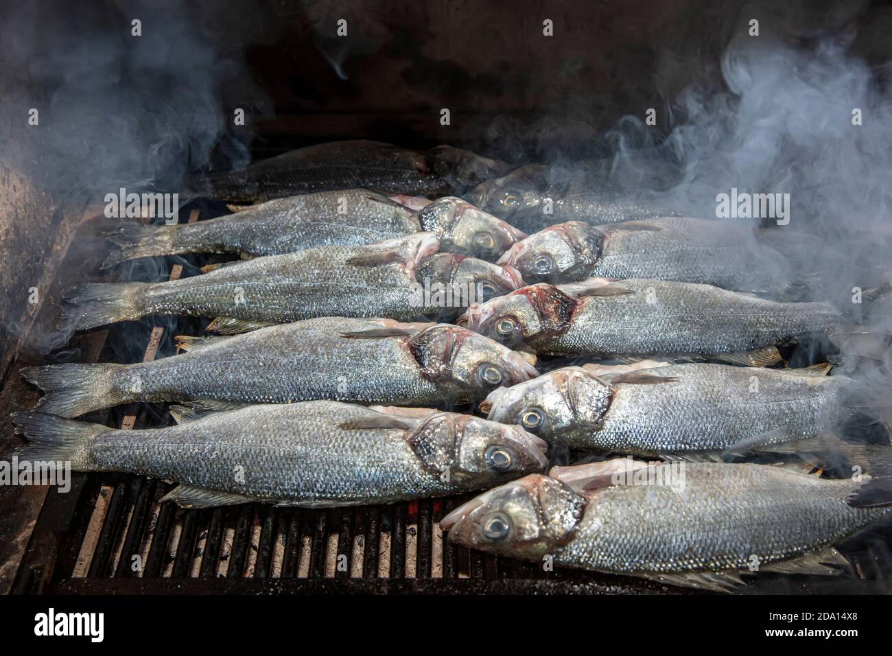 Grilled sea bass fish closeup. In process. European sea-bass, chef is ...